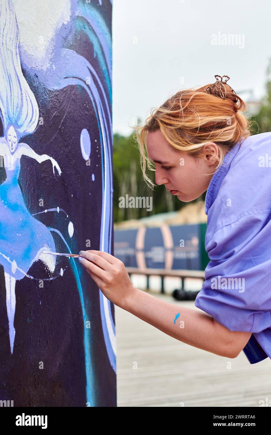 Female painter draws picture with paintbrush on canvas for outdoor ...