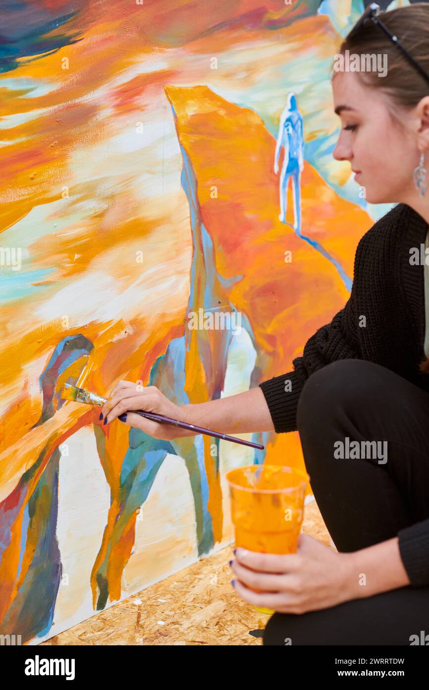 Attractive female painter passionately draws picture with paintbrush ...