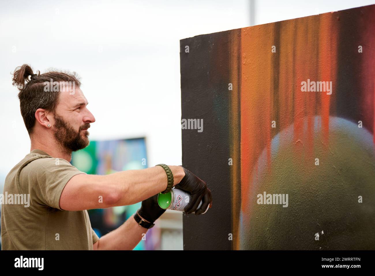 Attractive male artist is painting picture with paint spray can ...