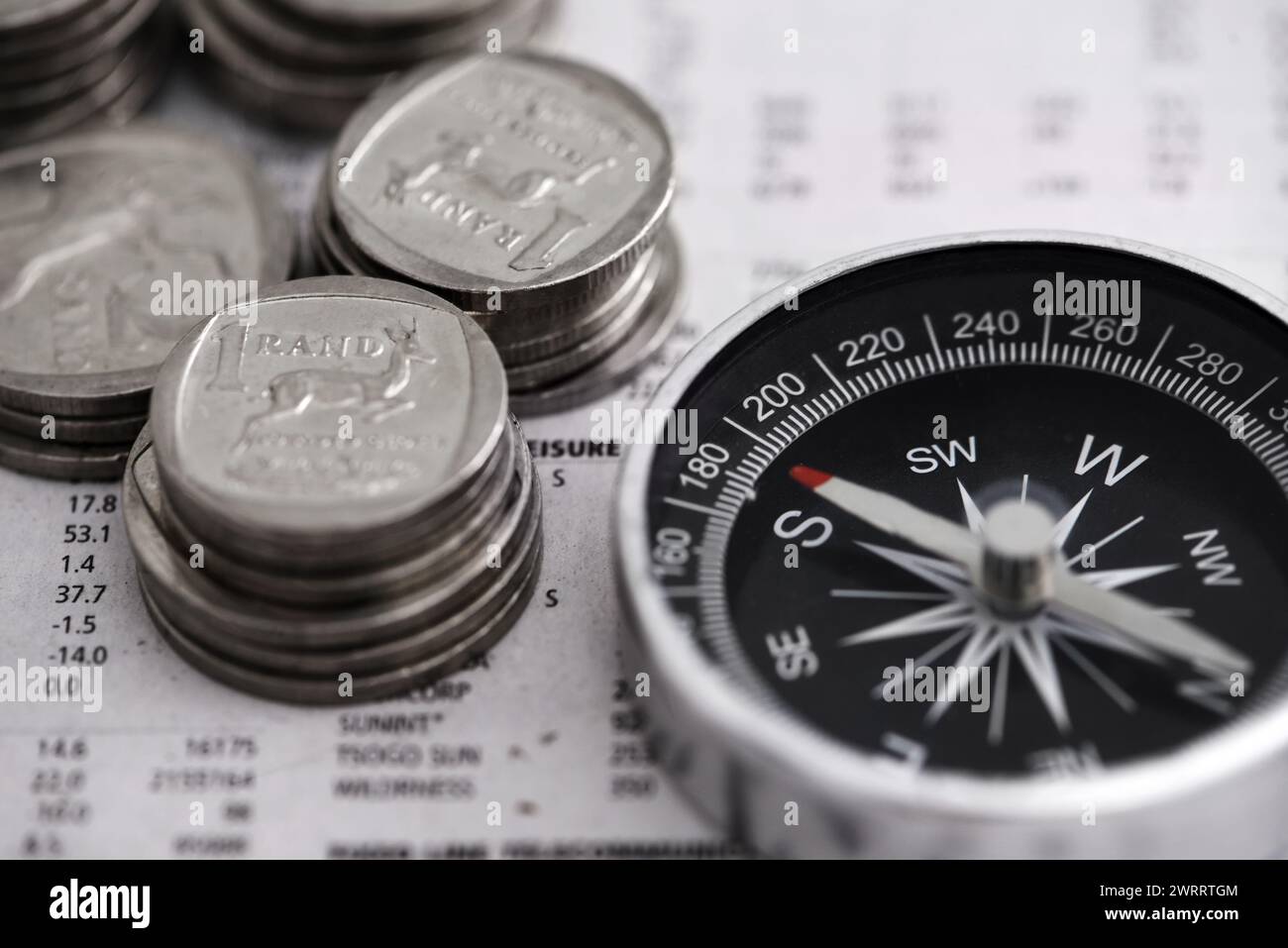 Coins, compass and business section of newspaper for exchange rate and ...