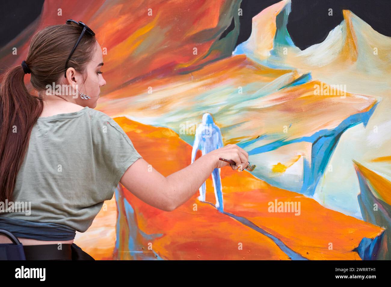 Attractive female painter passionately draws picture with paintbrush ...