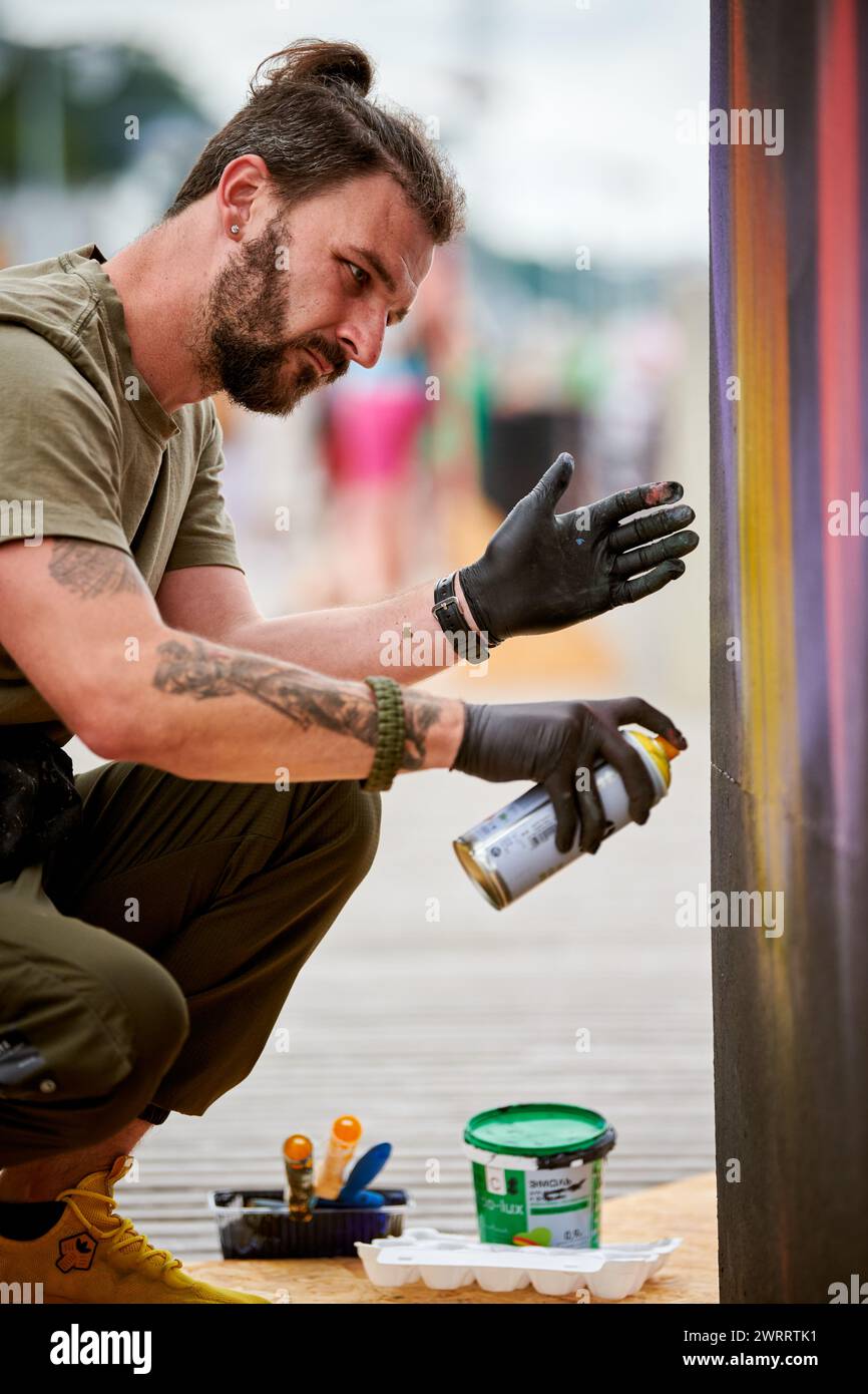 Attractive male artist is painting picture with paint spray can ...