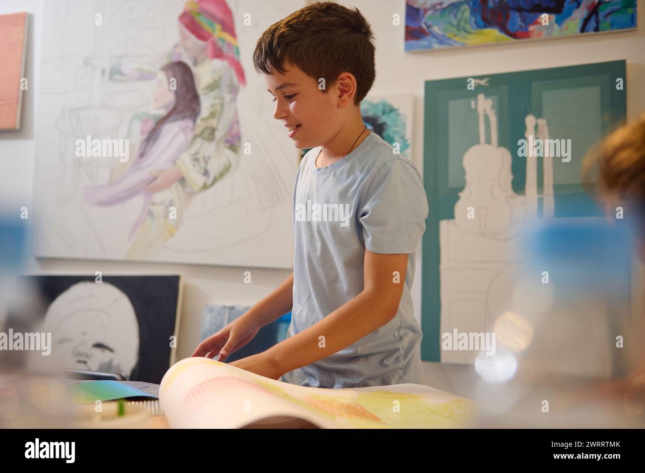 Smiling teenage boy in the art class, learning drawing and painting. Adolescent schoolboy ...