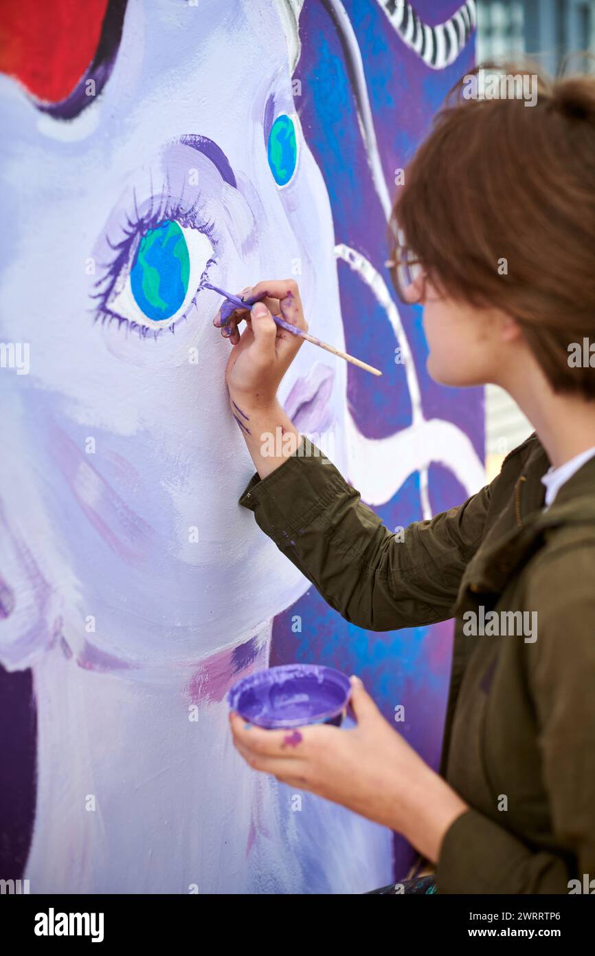 Female painter draws picture with paintbrush on canvas for outdoor ...