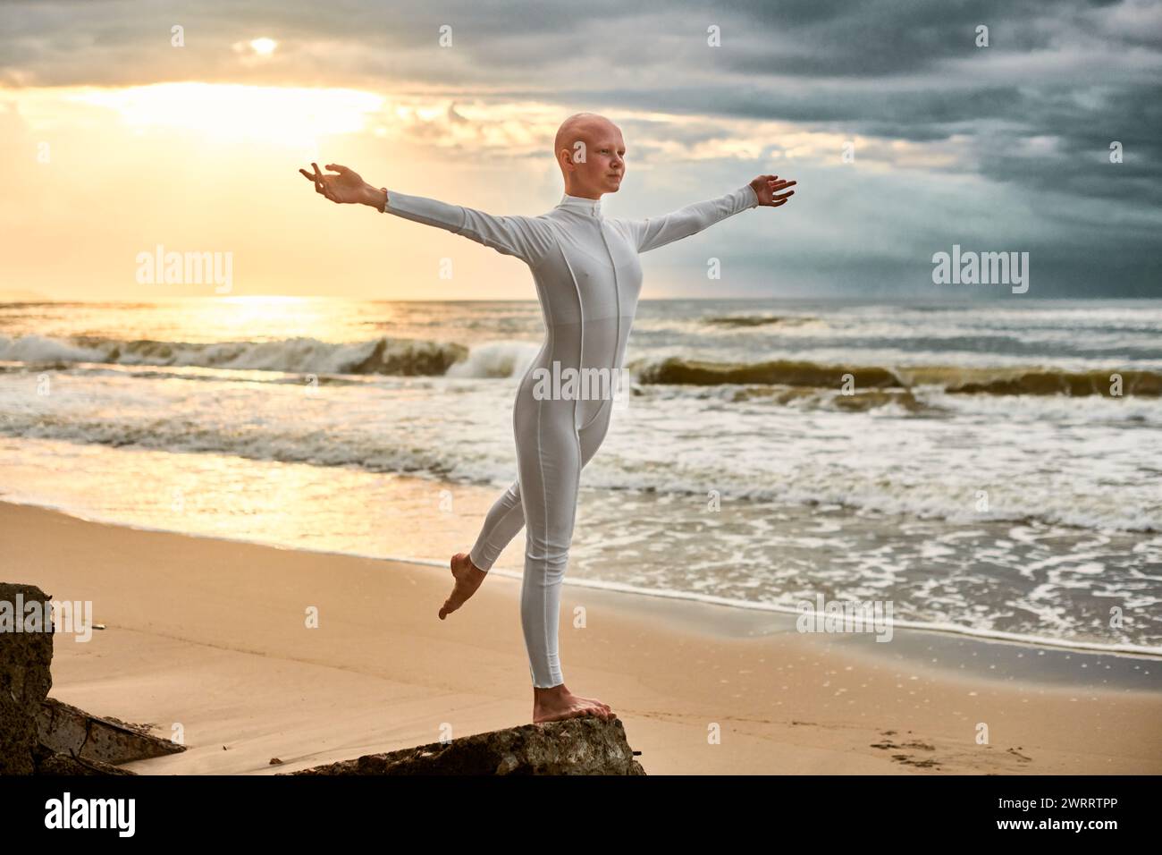 Young hairless ballerina with alopecia in white futuristic suit dancing ...