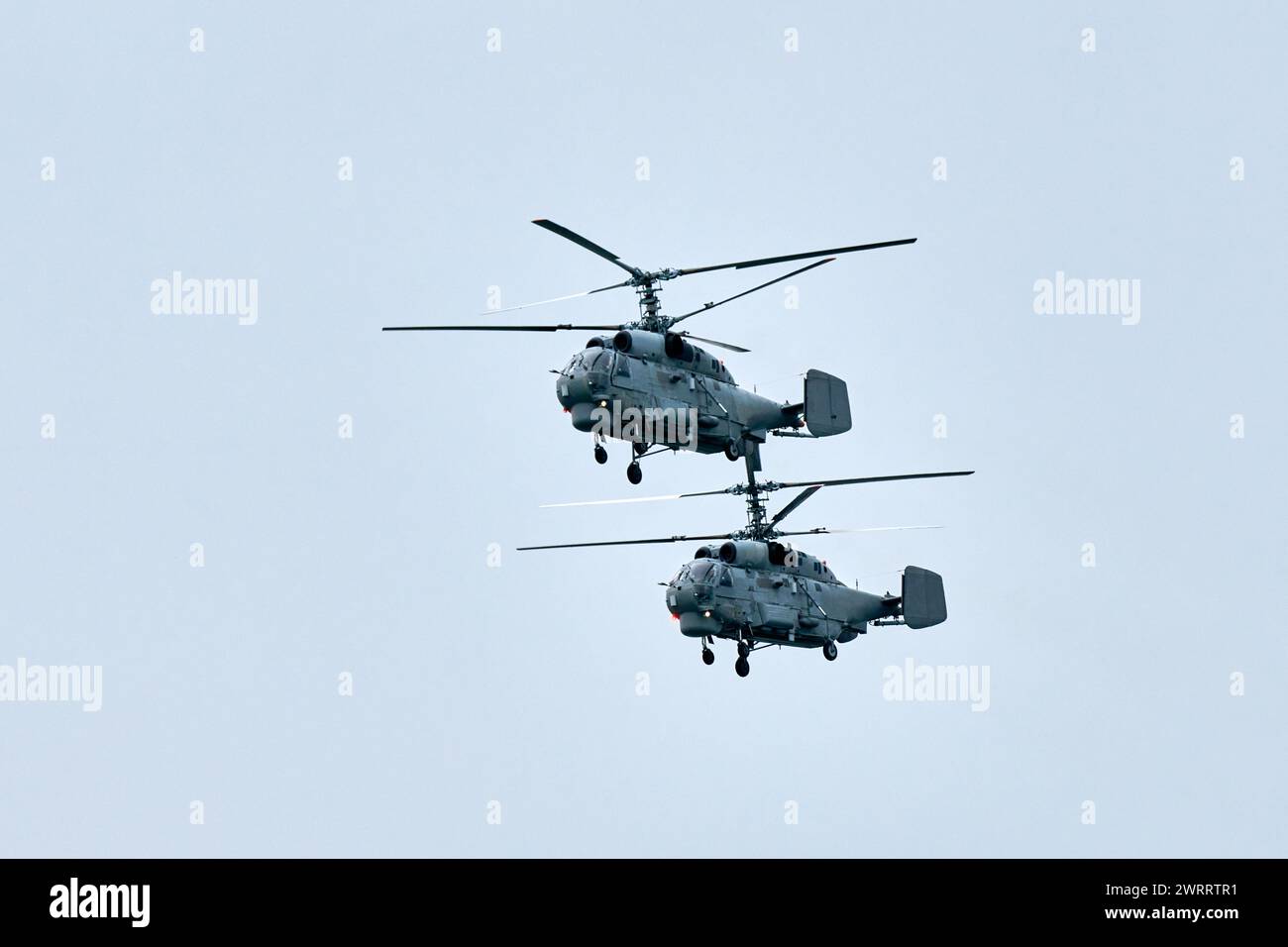 Two Russian military helicopters armed with missiles flies in blue sky ...