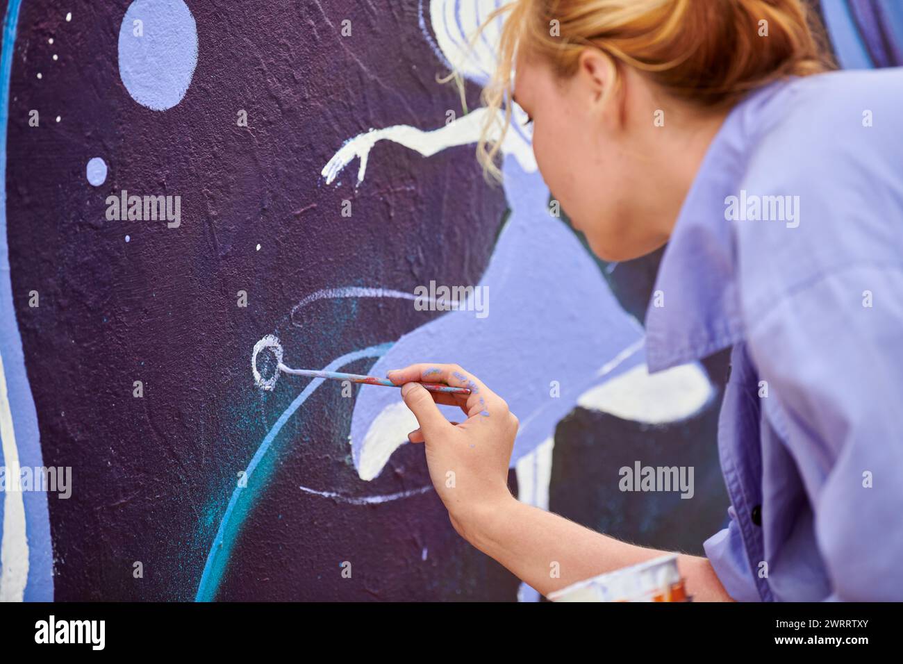 Female painter draws picture with paintbrush on canvas for outdoor ...