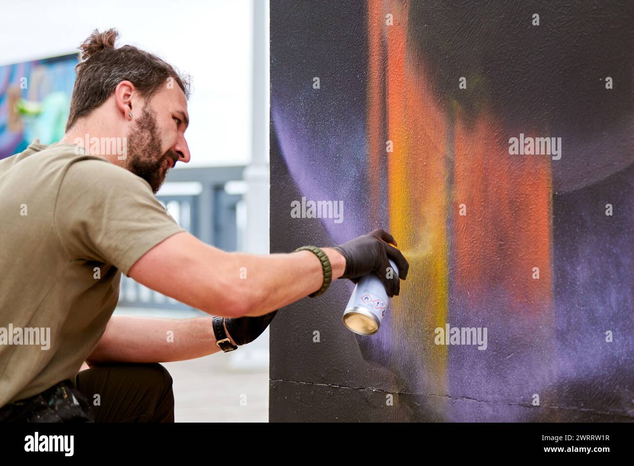 Attractive male artist is painting picture with paint spray can ...