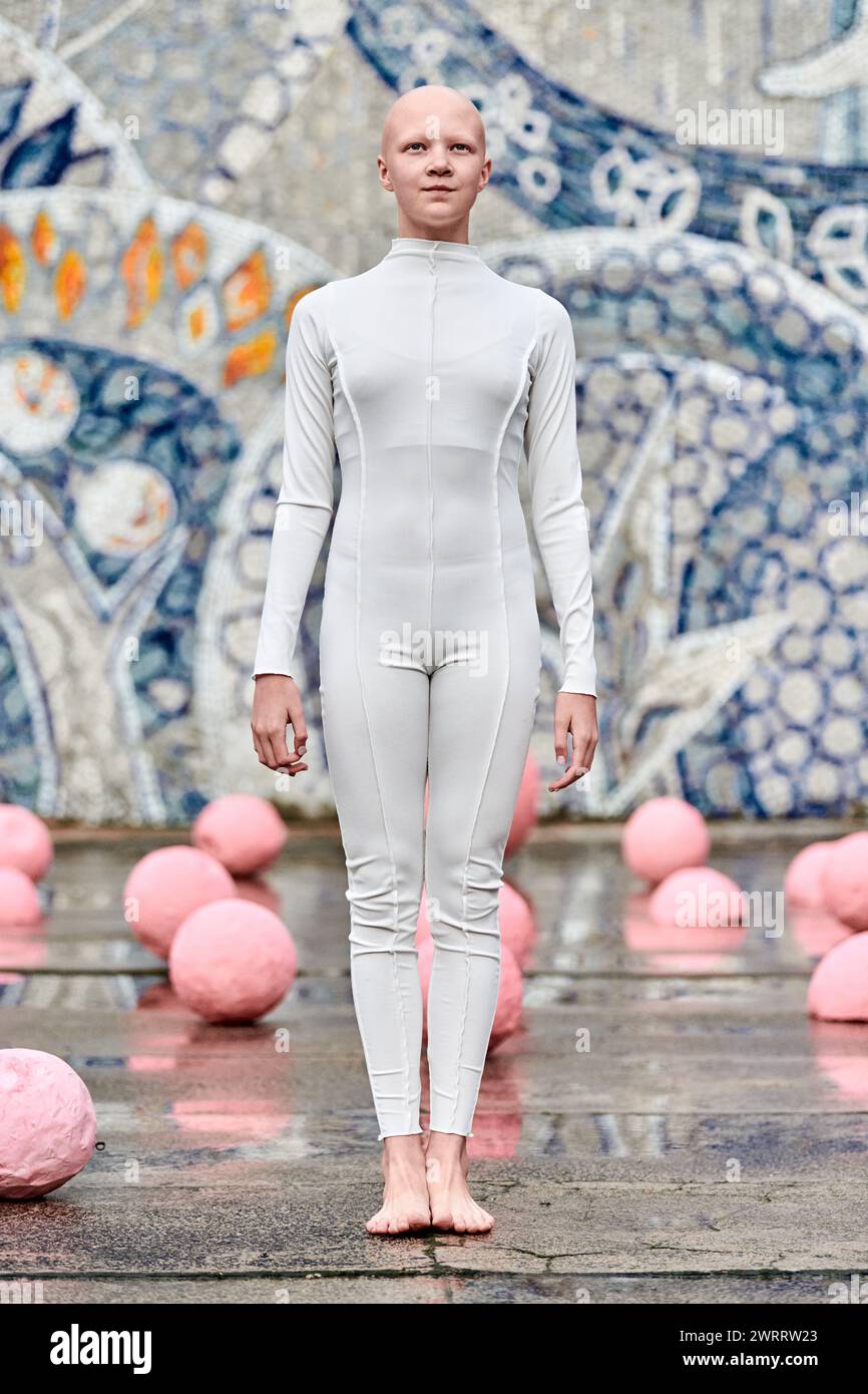 Young hairless girl ballerina with alopecia in white futuristic suit ...