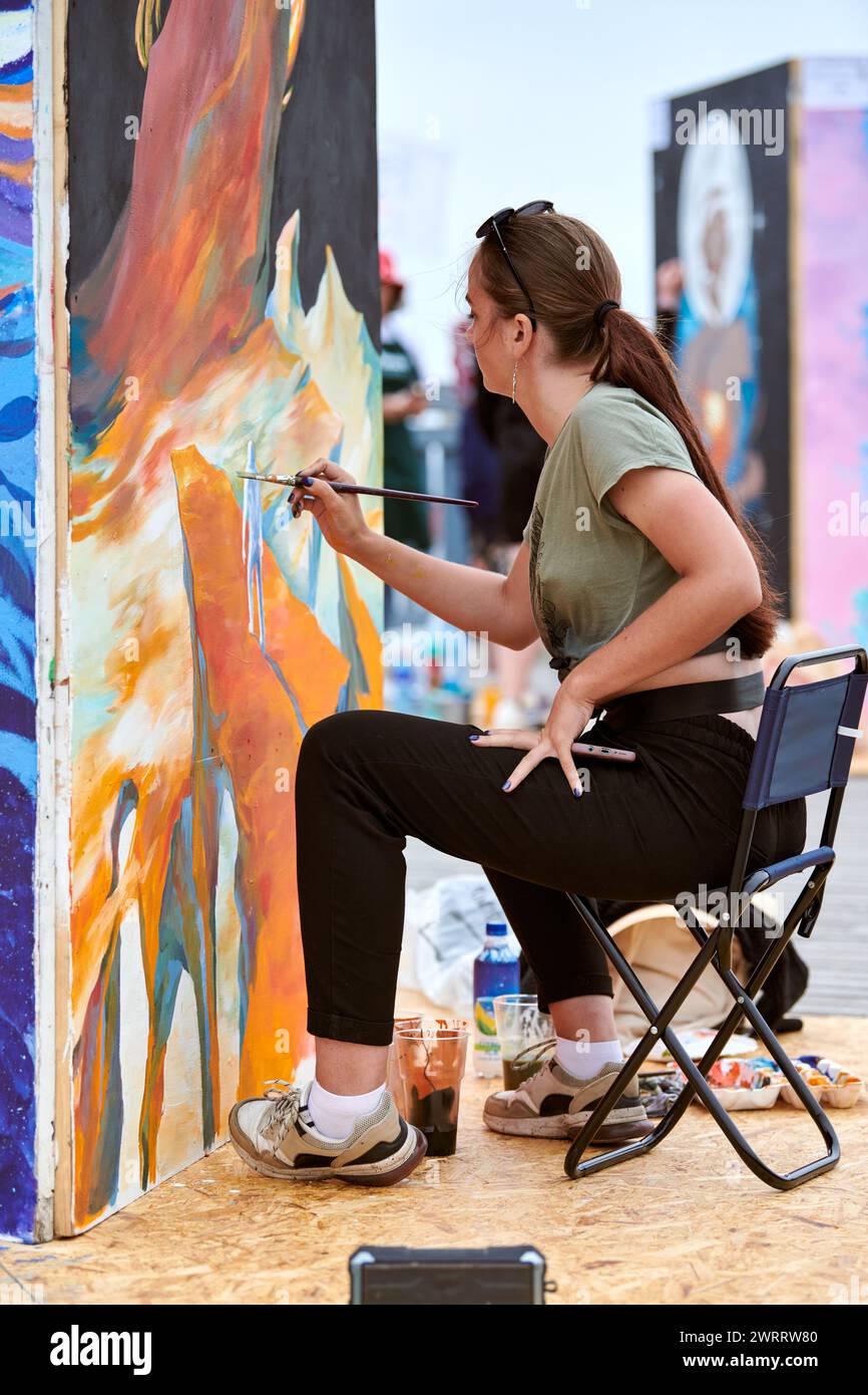 Attractive female painter passionately draws picture with paintbrush ...