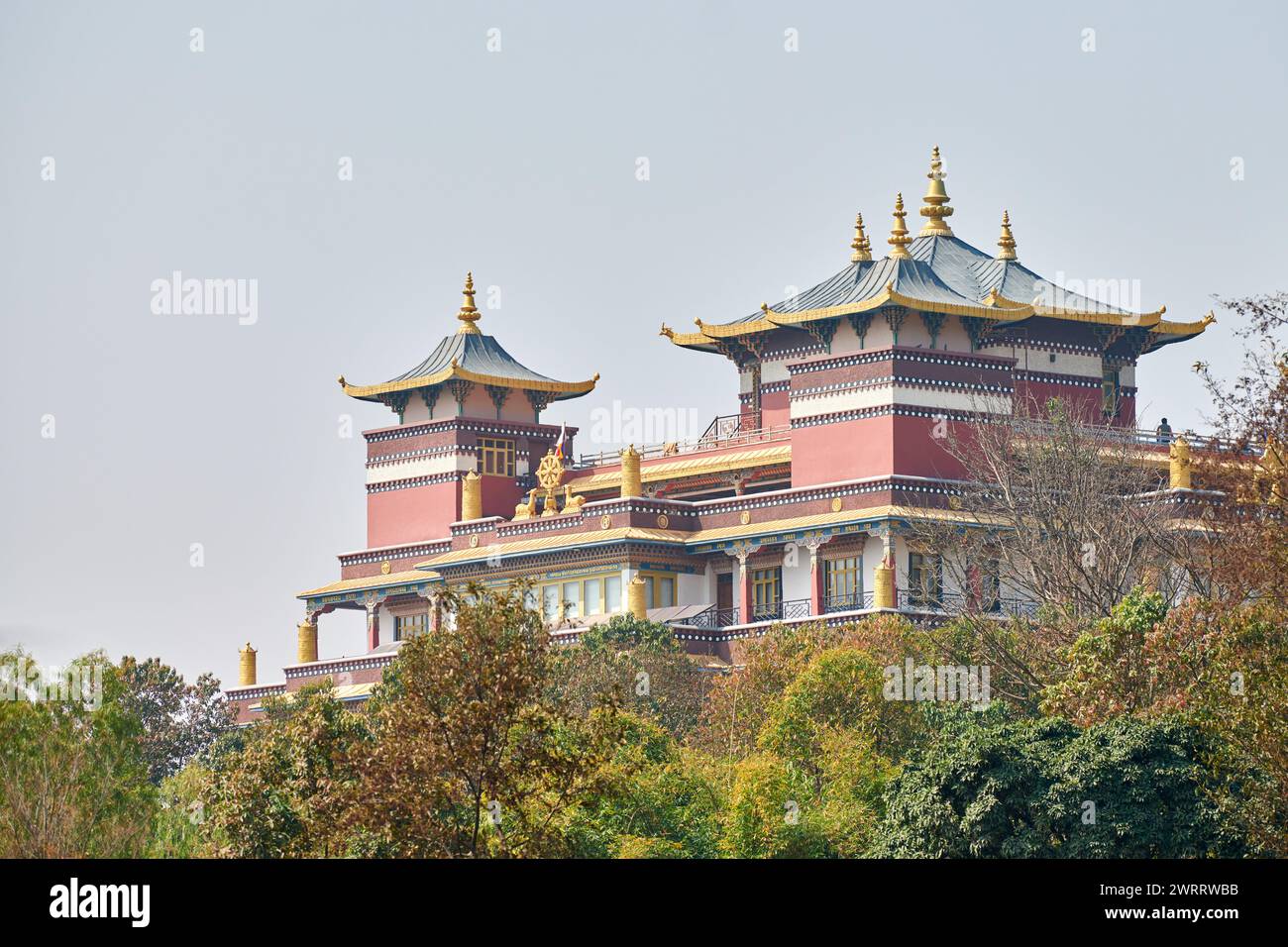 Tibetan temple on mountain shrouded in green vegetation amidst peaceful ...