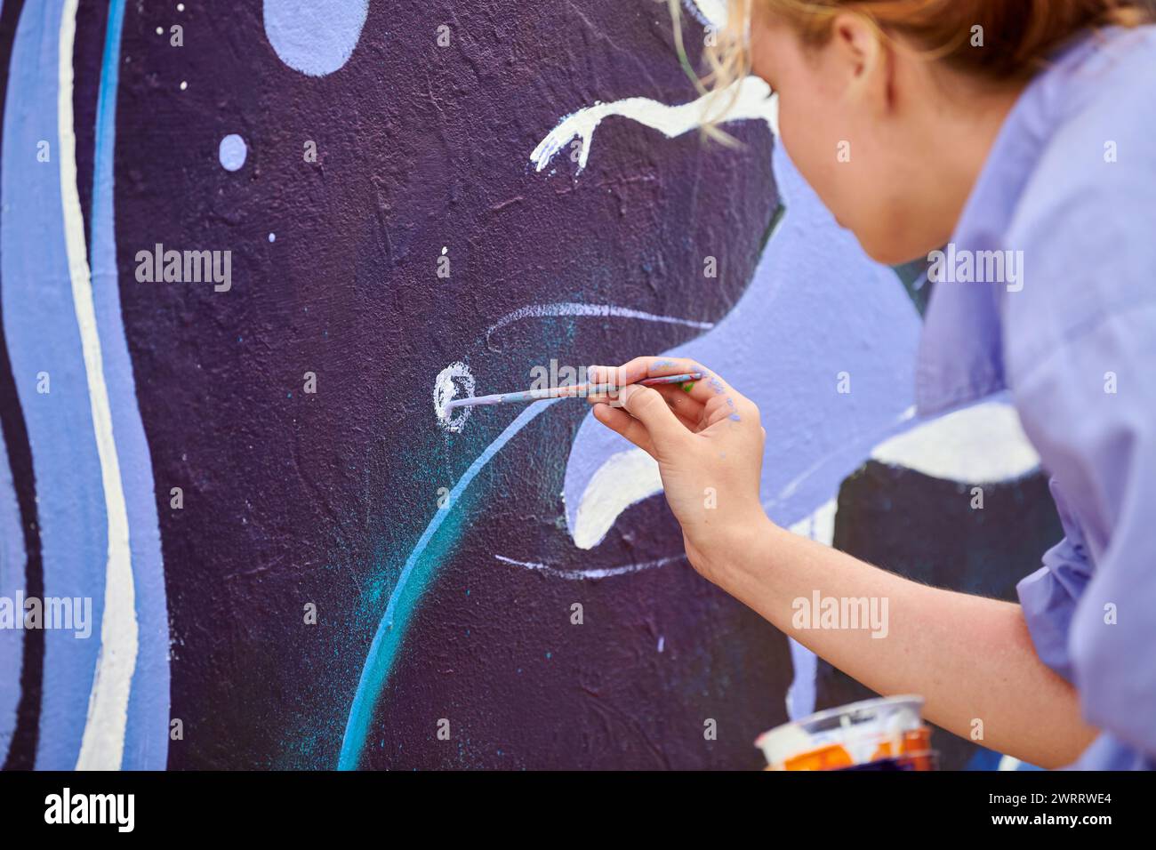 Female painter draws picture with paintbrush on canvas for outdoor ...