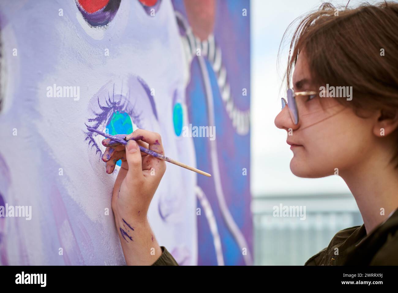 Female painter draws picture with paintbrush on canvas for outdoor ...