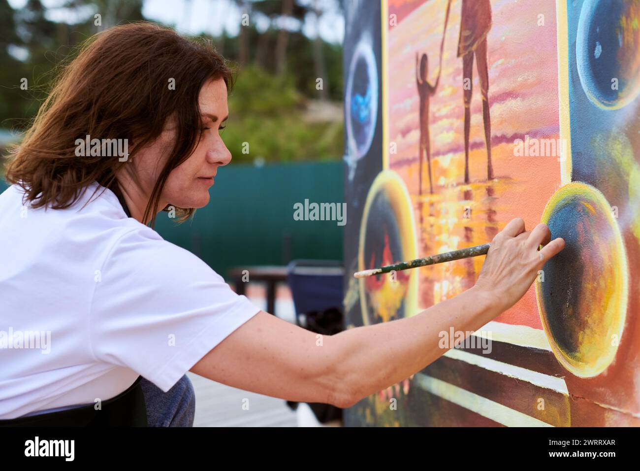 Female painter draws picture with paintbrush on canvas for outdoor ...