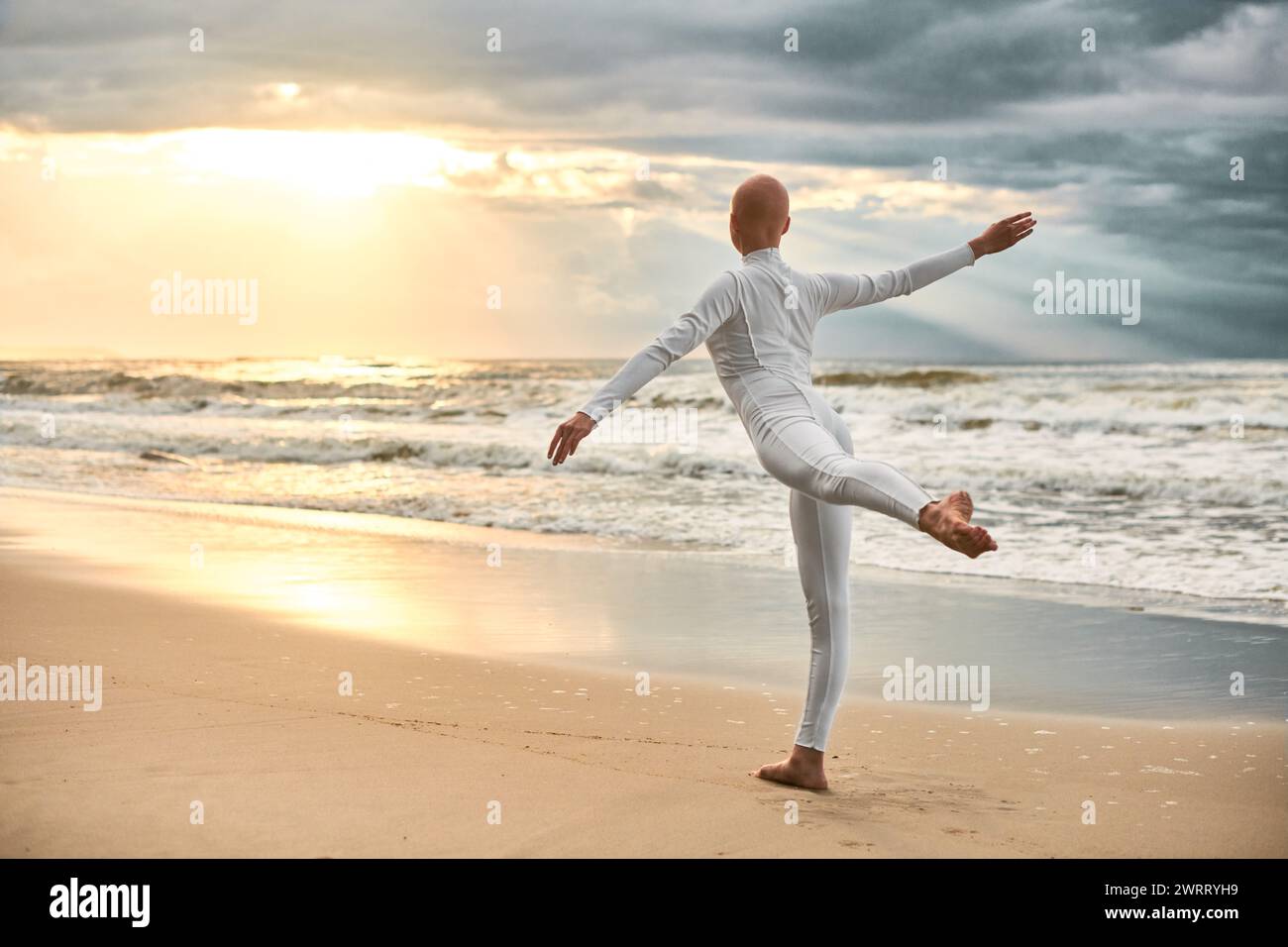 Young hairless ballerina with alopecia in white futuristic suit dancing ...