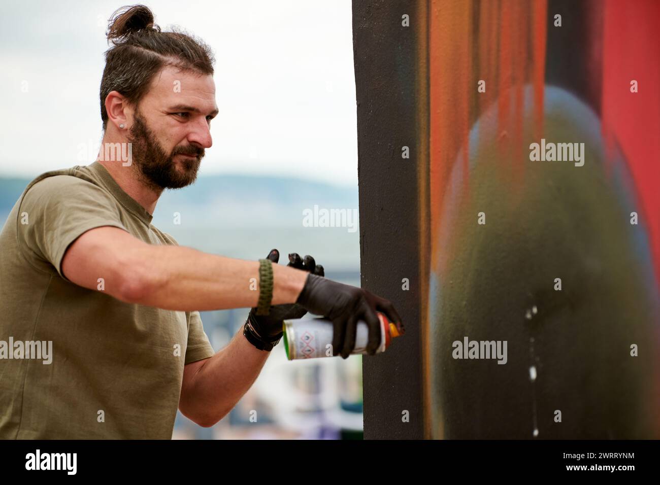 Attractive male artist is painting picture with paint spray can ...