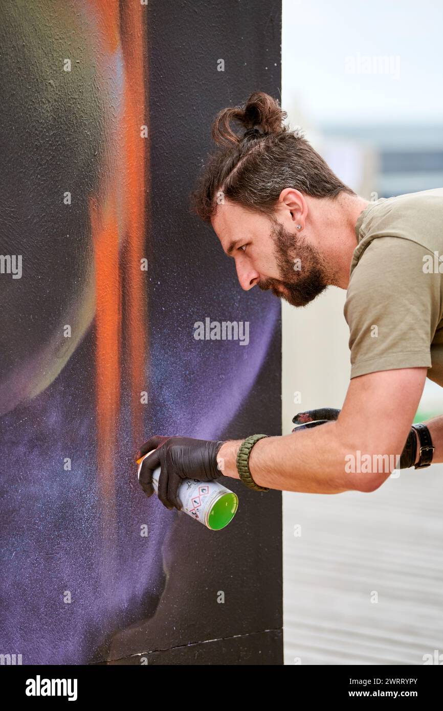 Attractive male artist is painting picture with paint spray can ...