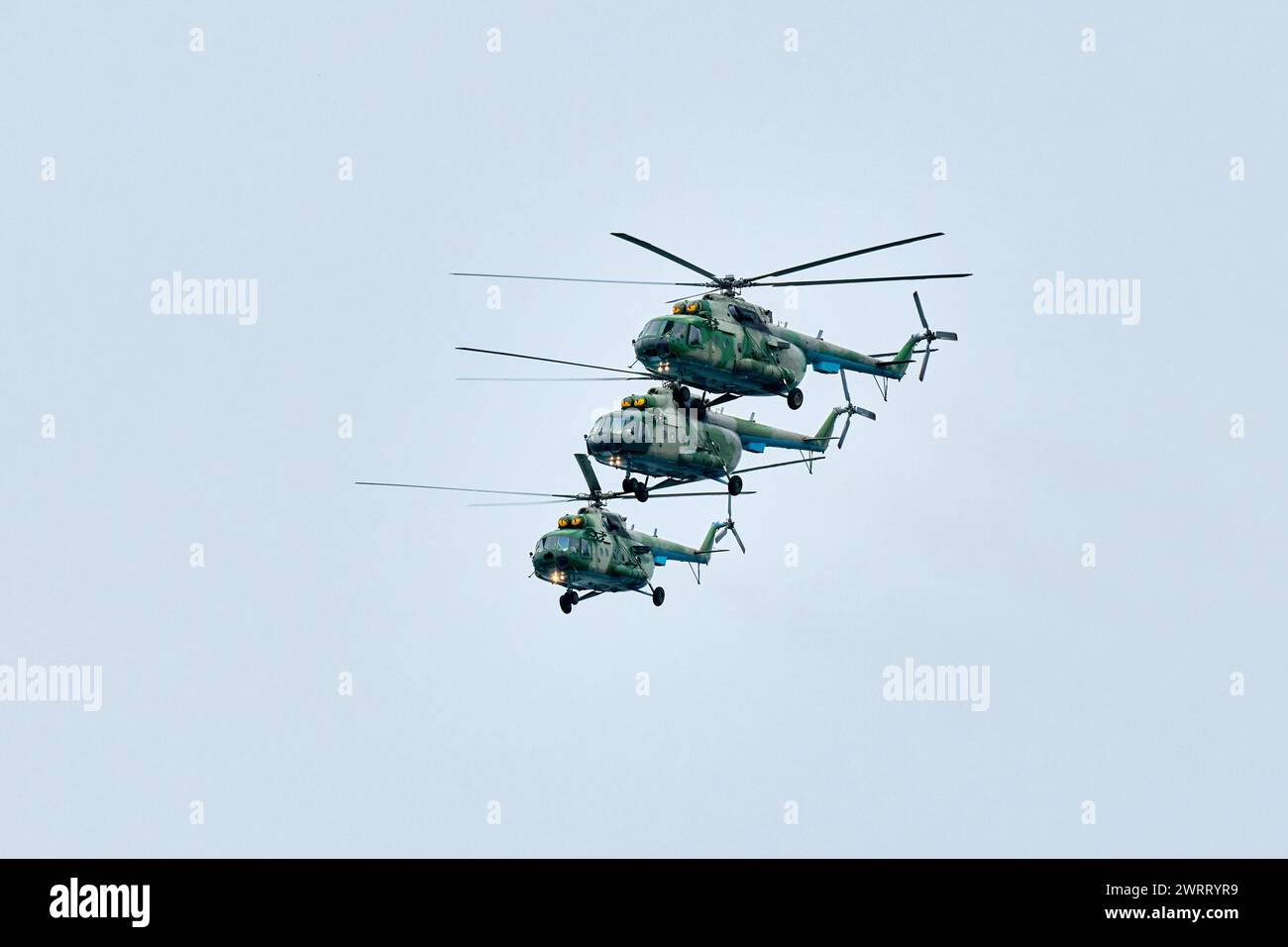 Three Russian military helicopters armed with missiles flies in blue ...