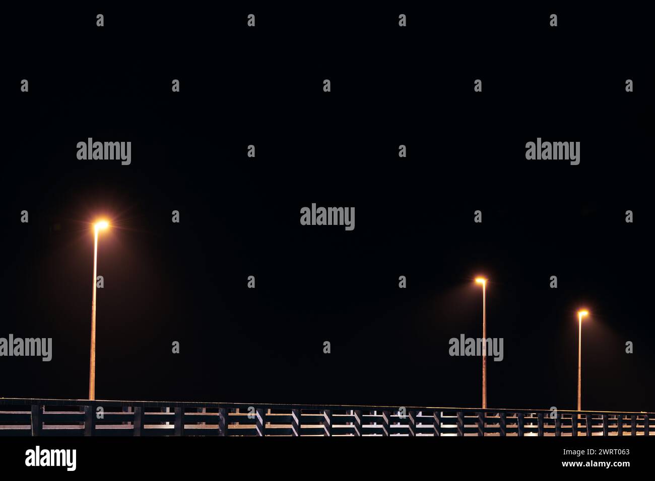 Street lampposts casts dim yellow warm along shore pier standing ...