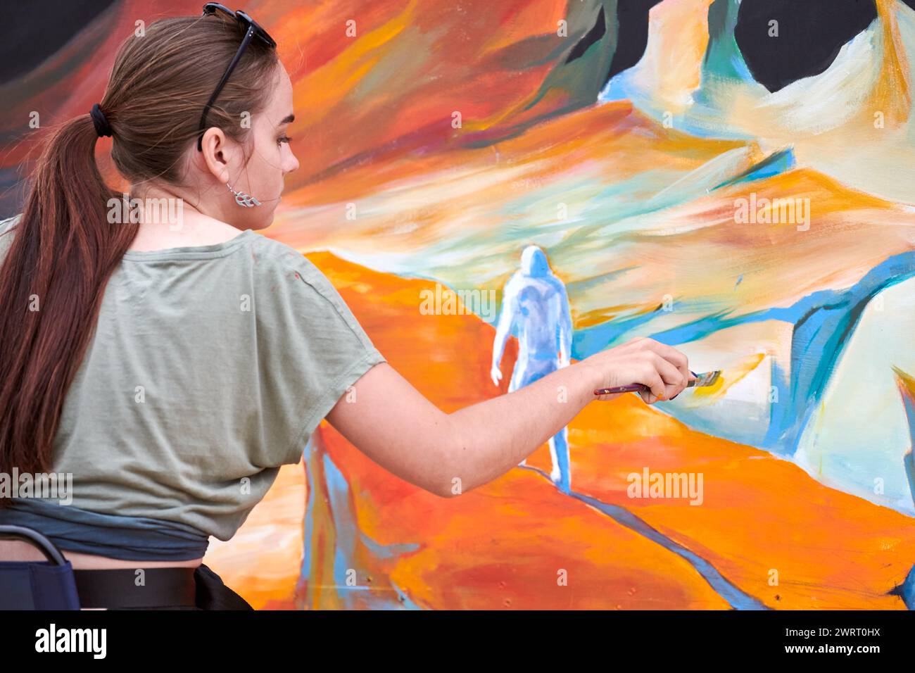 Attractive female painter passionately draws picture with paintbrush ...