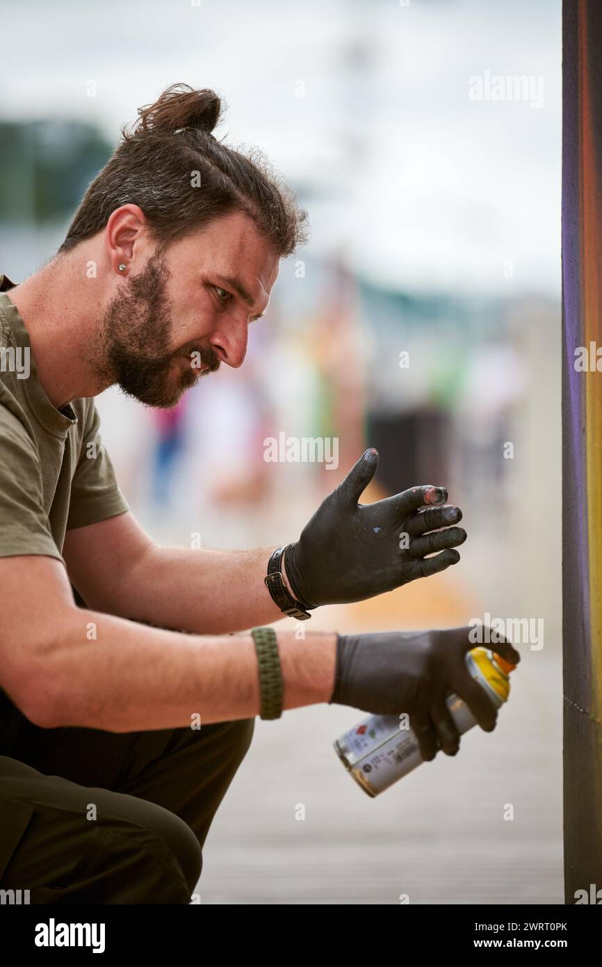 Attractive male artist is painting picture with paint spray can ...