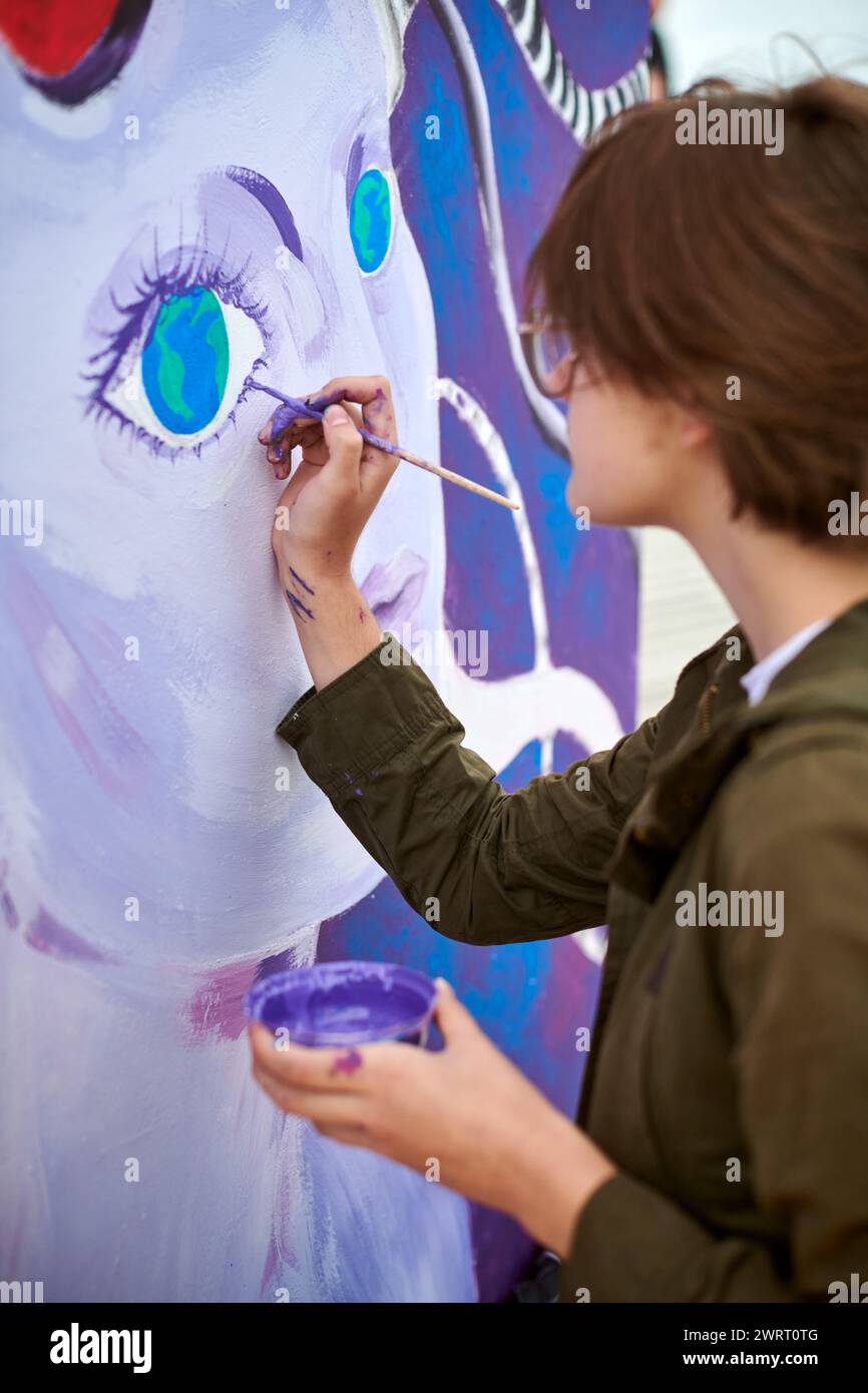 Female painter draws picture with paintbrush on canvas for outdoor ...