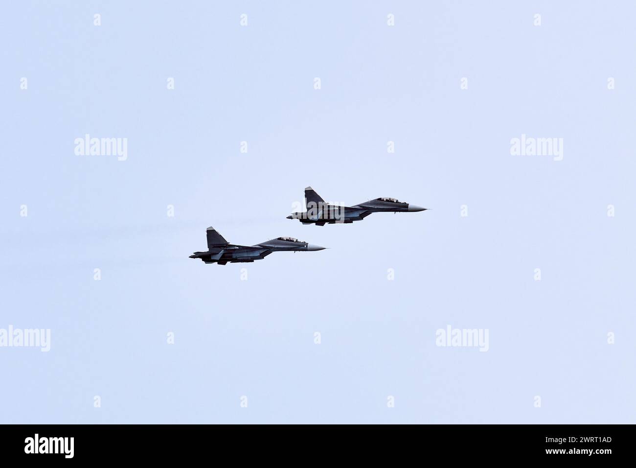 Two Russian military fighter planes armed with missiles flies in blue ...