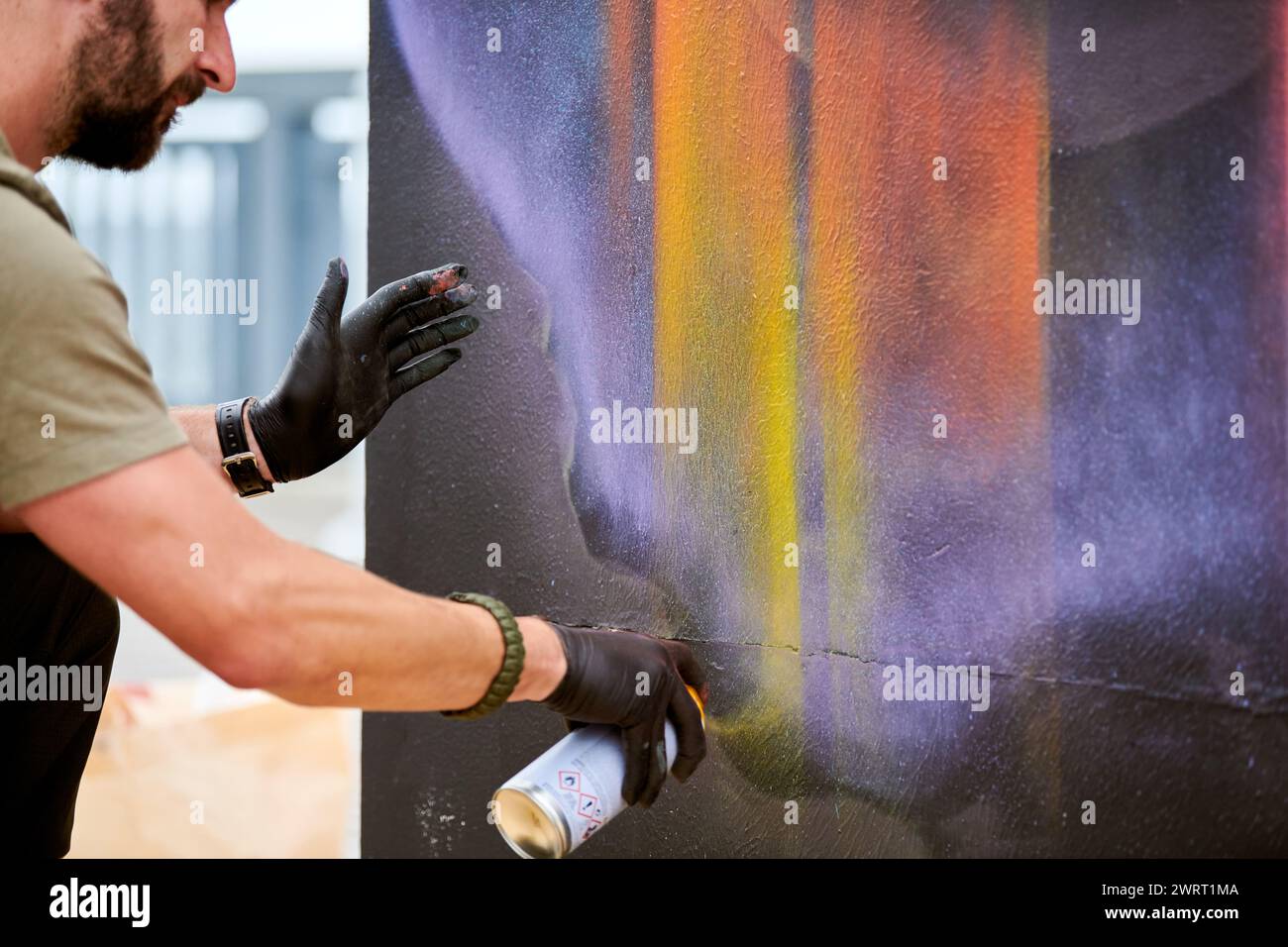 Attractive male artist is painting picture with paint spray can ...