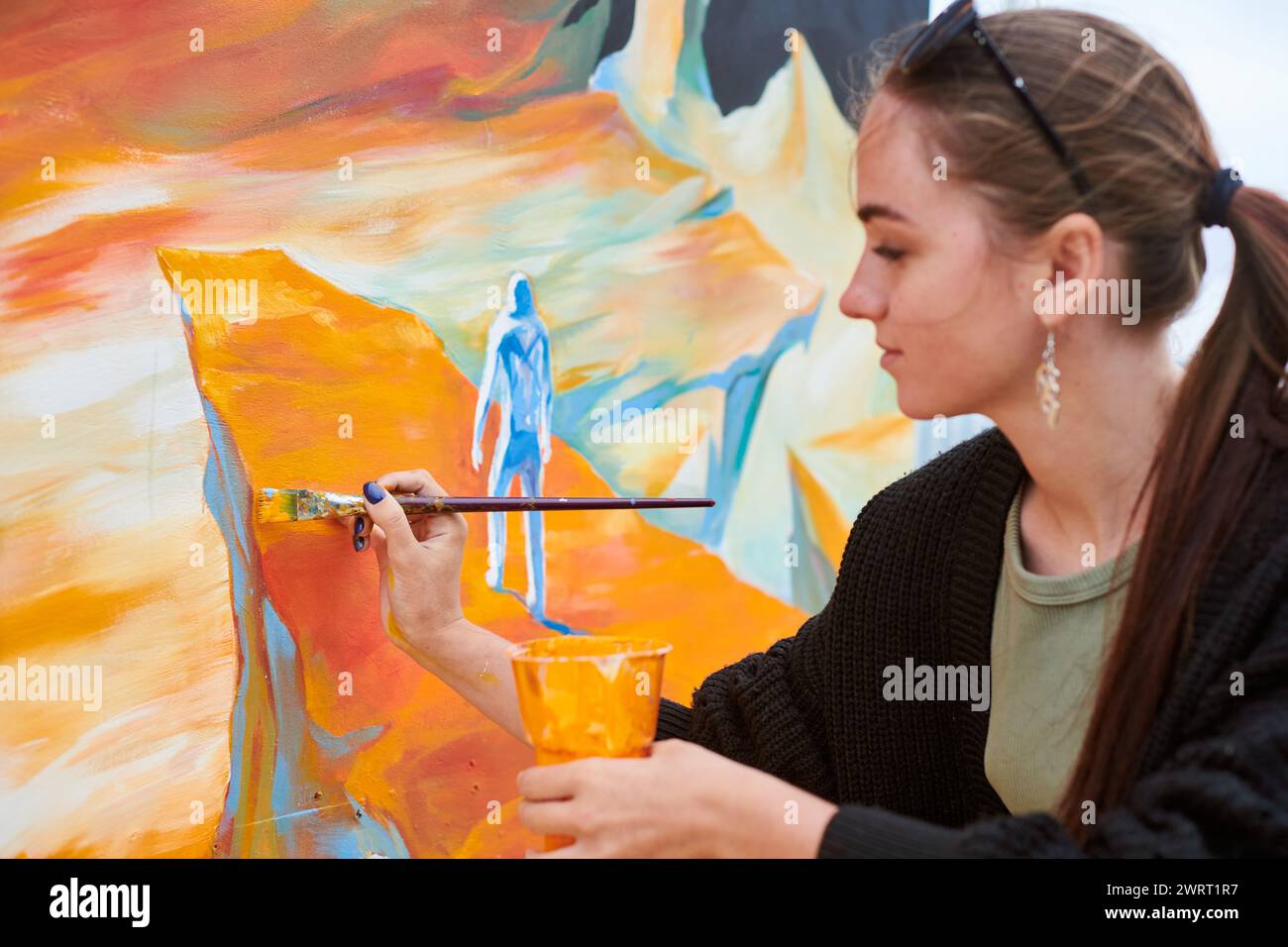 Attractive female painter passionately draws picture with paintbrush ...