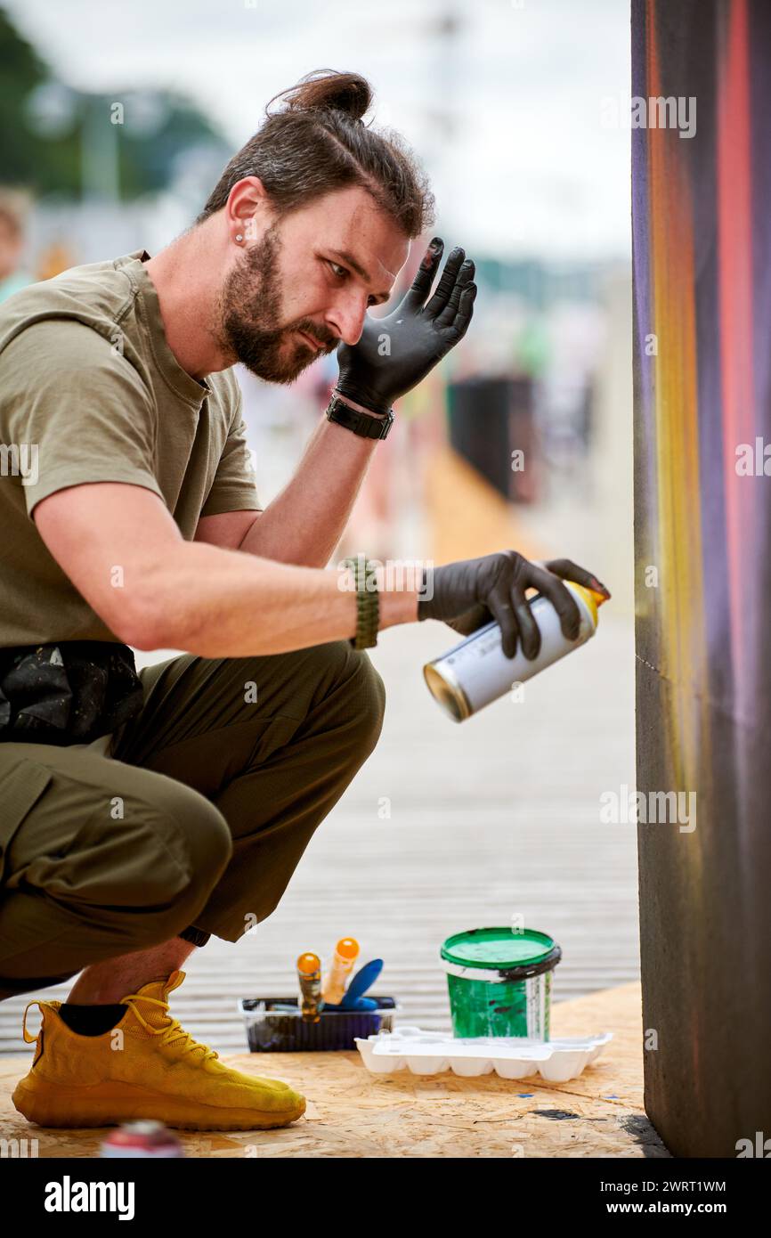 Attractive male artist is painting picture with paint spray can ...