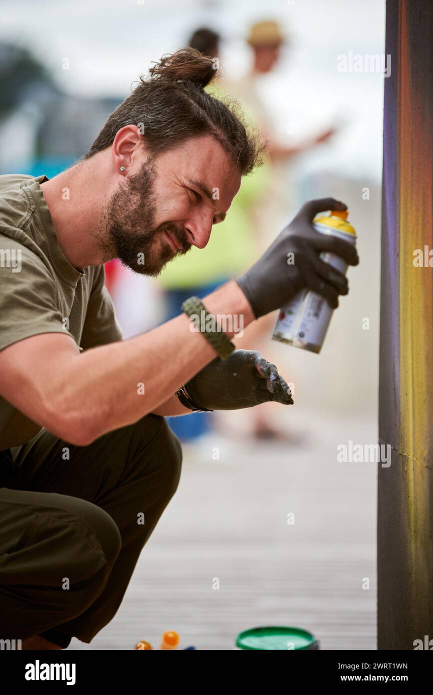 Attractive male artist is painting picture with paint spray can ...