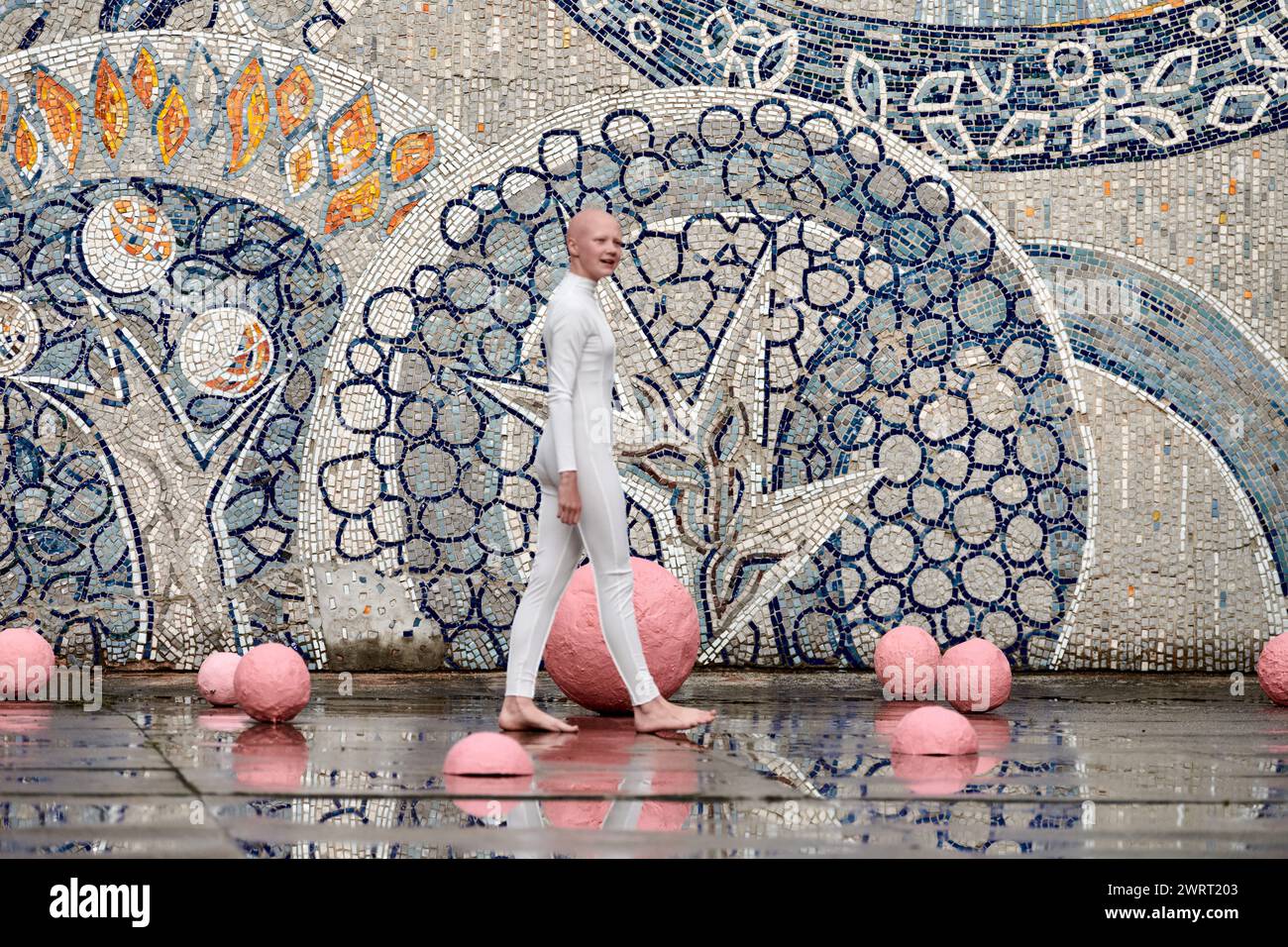 Young hairless girl ballerina with alopecia in white futuristic suit ...
