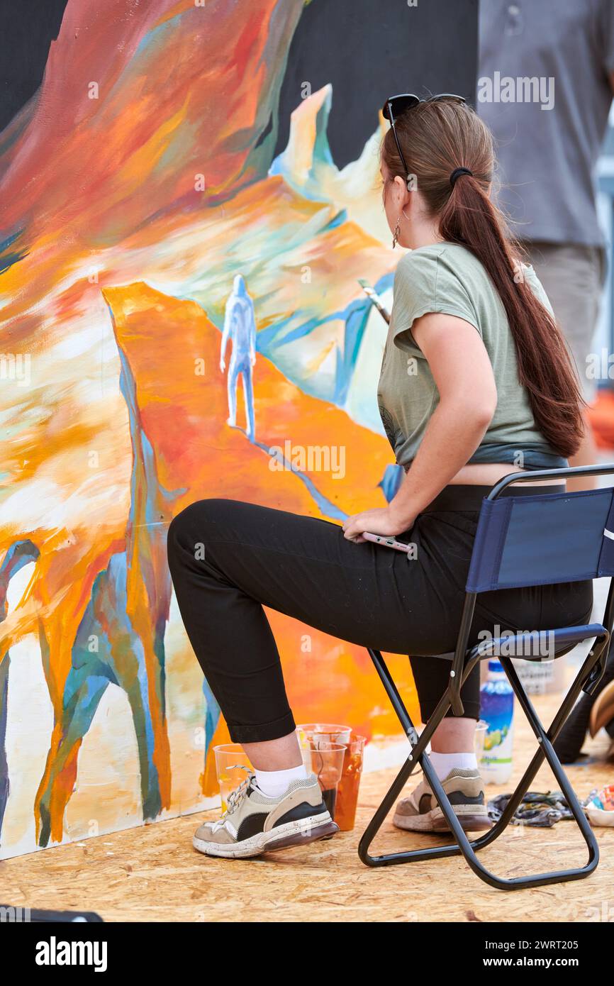 Attractive female painter passionately draws picture with paintbrush ...