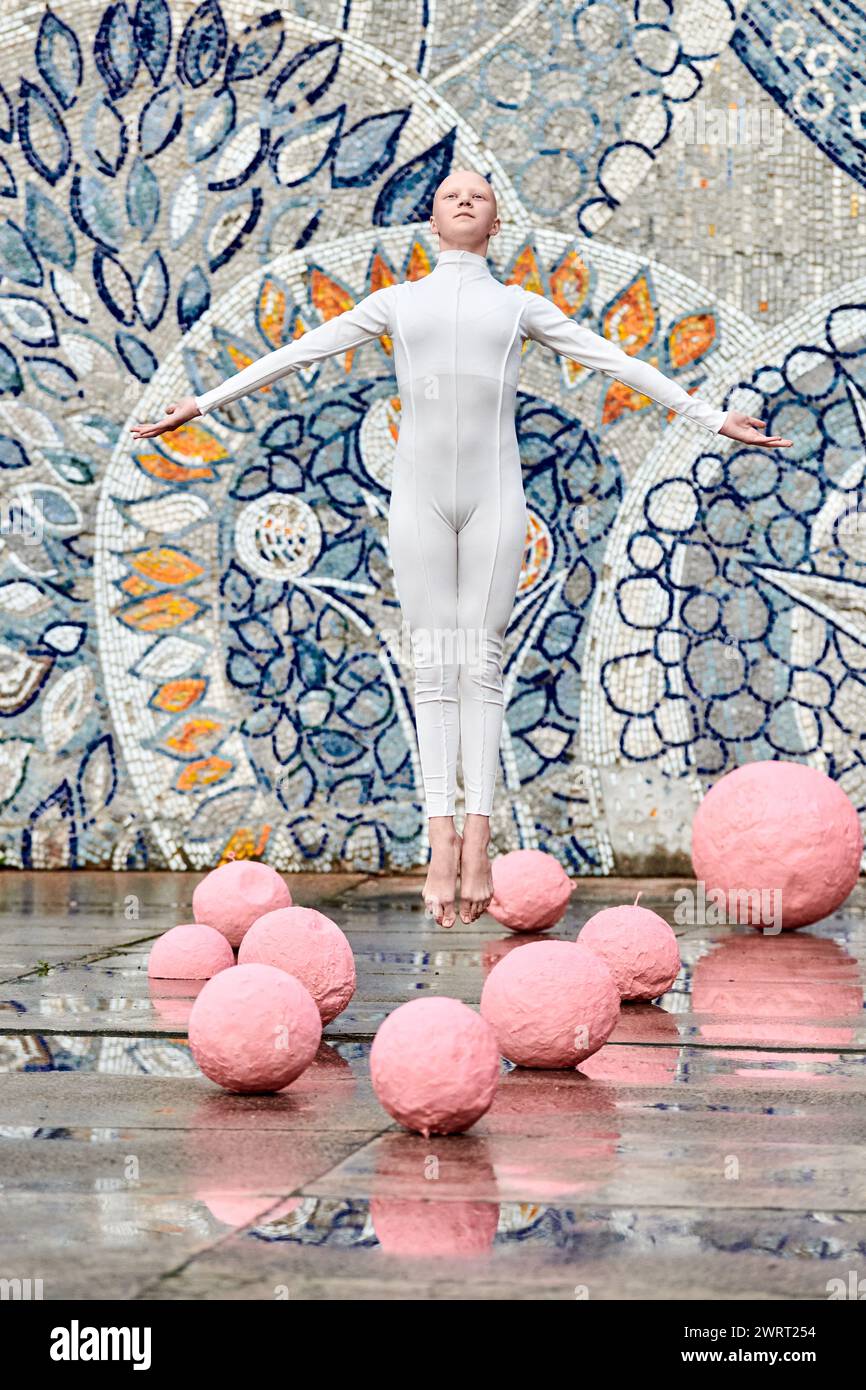 Young hairless girl ballerina with alopecia in white futuristic suit ...