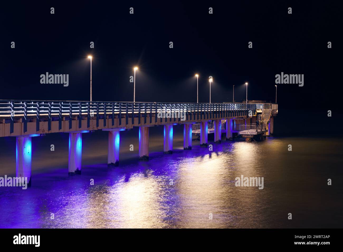 Sea pier adorned multicolored twinkling lights at night symbolizes ...