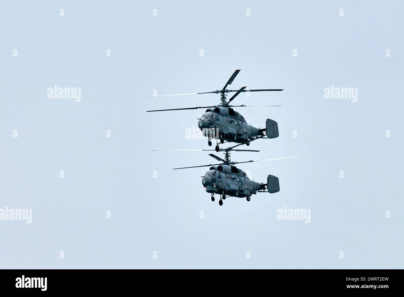 Two Russian military helicopters armed with missiles flies in blue sky ...