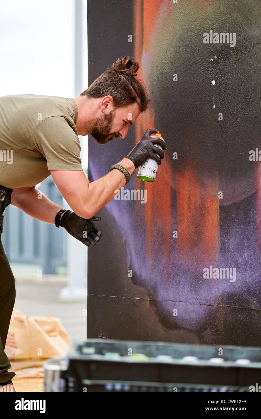 Attractive male artist is painting picture with paint spray can ...