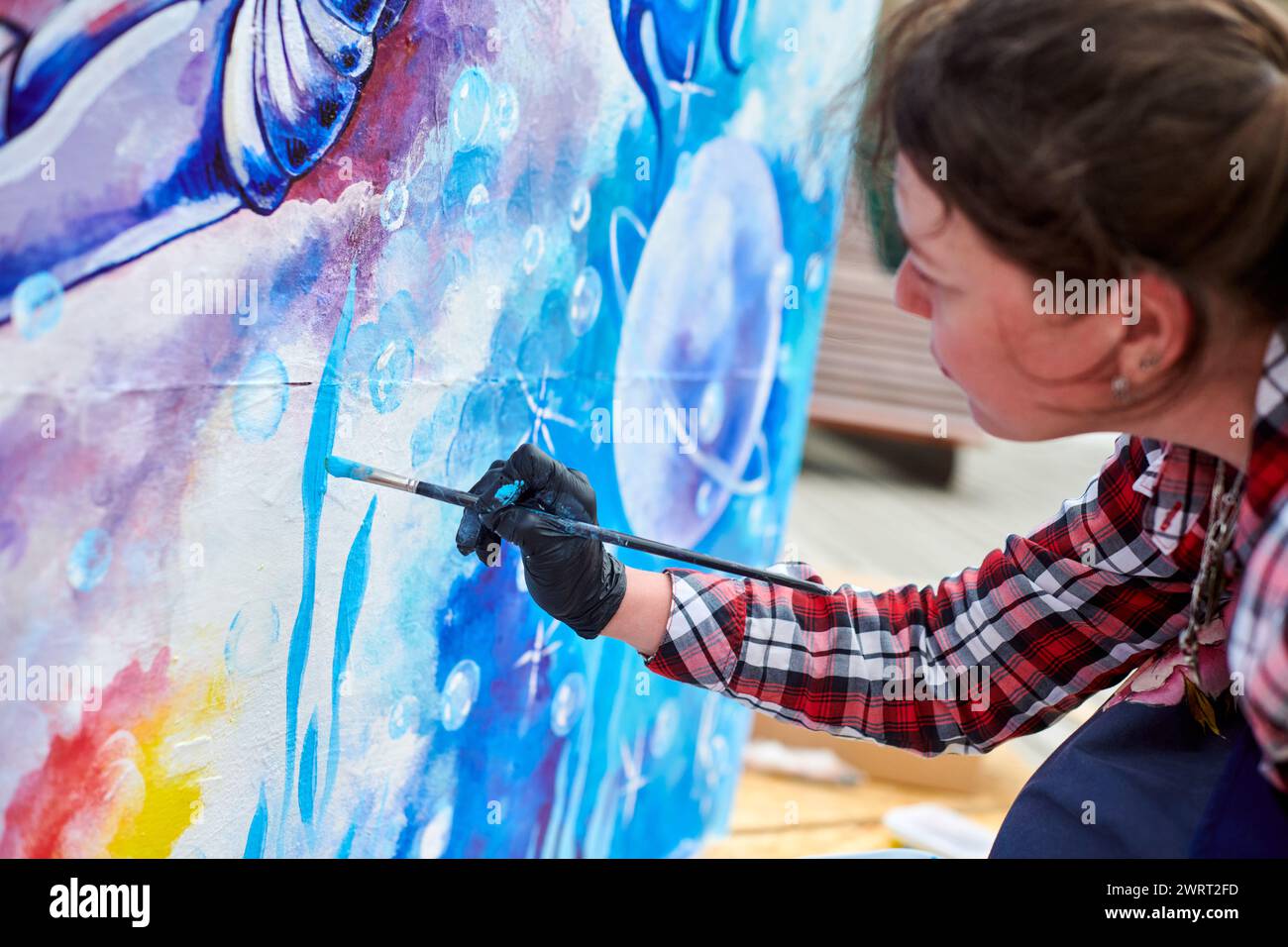 Female painter draws picture with paintbrush on canvas for outdoor ...