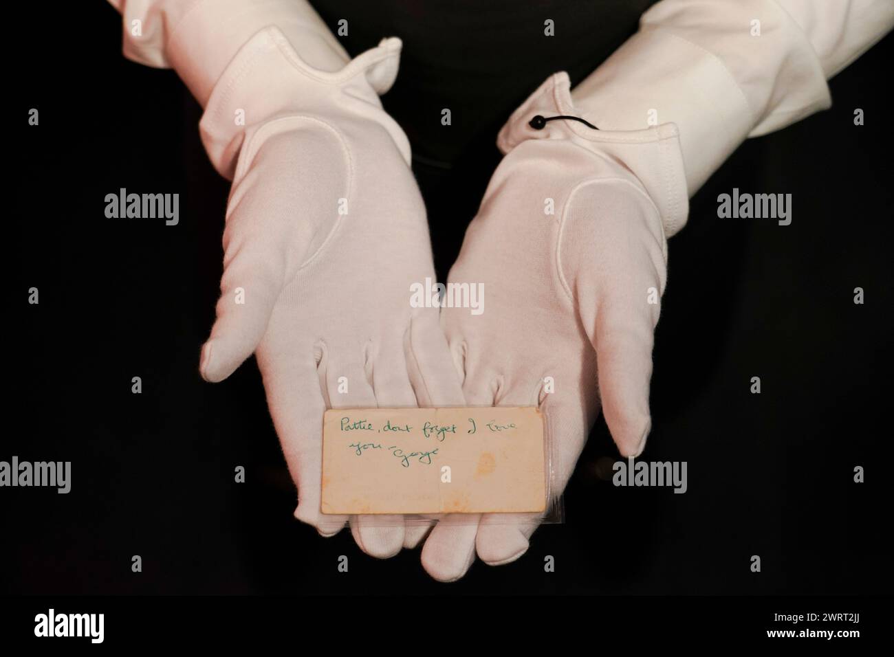 A member of staff holds a handwritten note by George Harrison, as part ...