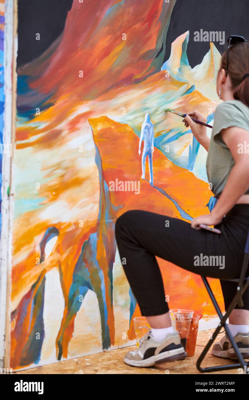 Attractive female painter passionately draws picture with paintbrush ...