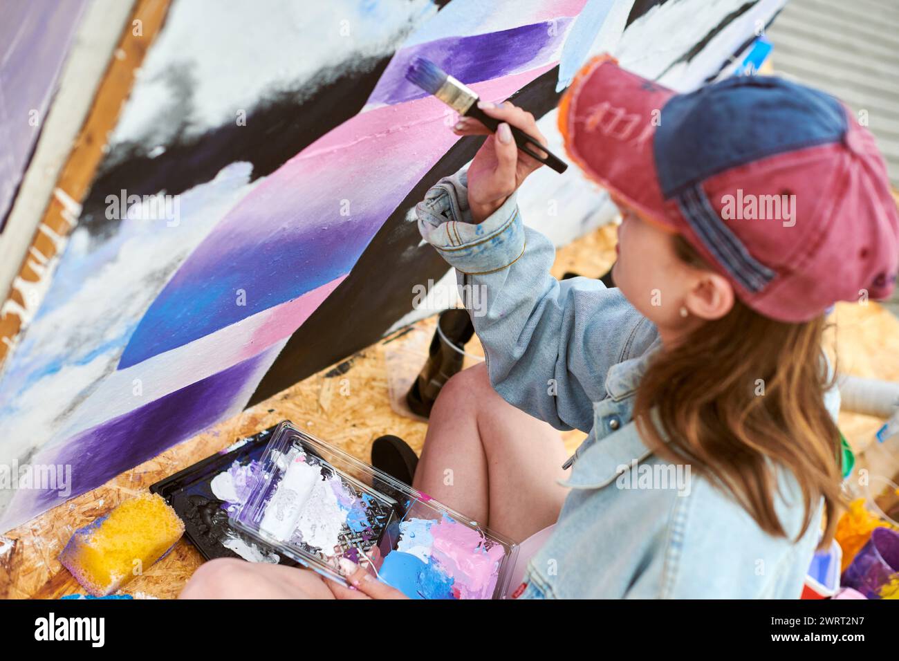Female painter draws picture with paintbrush on canvas for outdoor ...