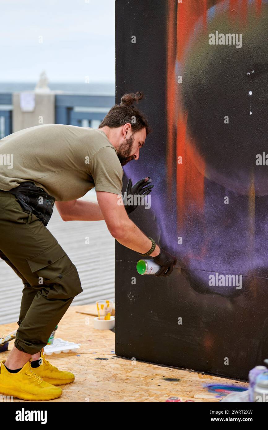 Attractive male artist is painting picture with paint spray can ...