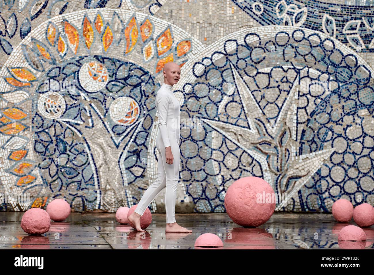 Young hairless girl ballerina with alopecia in white futuristic suit ...