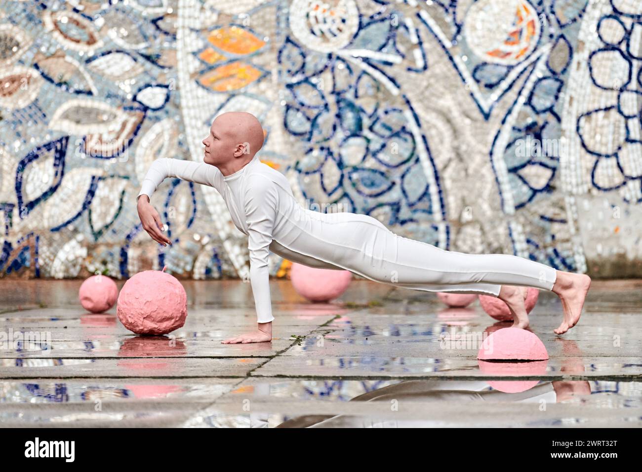 Outdoor dance of young ballerina girl with alopecia in white futuristic ...