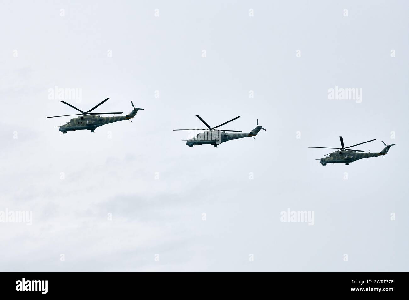 Three Russian military helicopters armed with missiles flies in blue ...