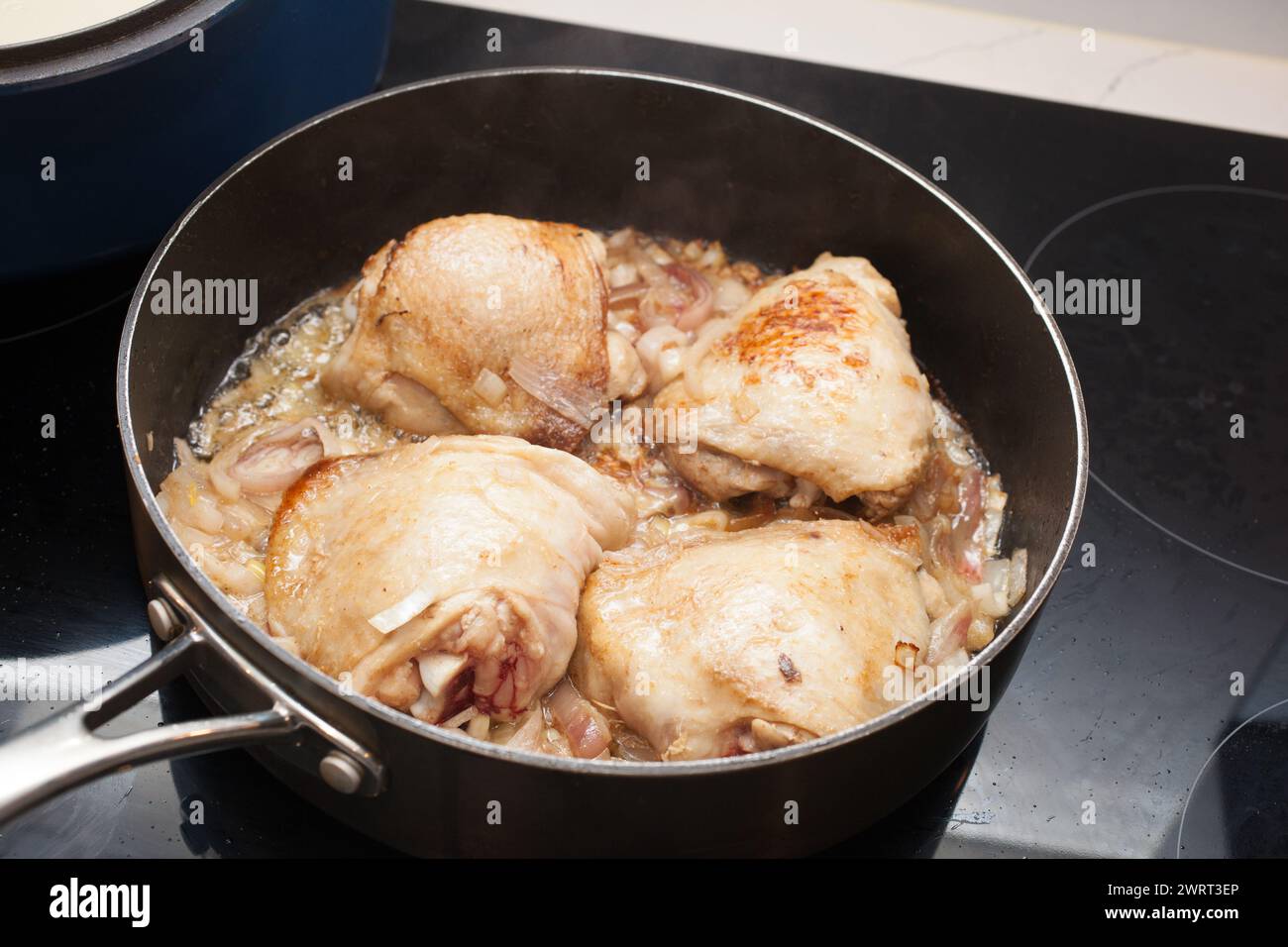 Chicken thighs being cooked in a pan on a hob Stock Photo - Alamy
