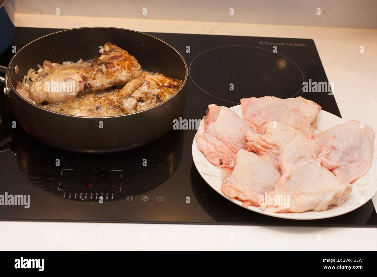 Batch cooking chicken thighs in a pan Stock Photo - Alamy