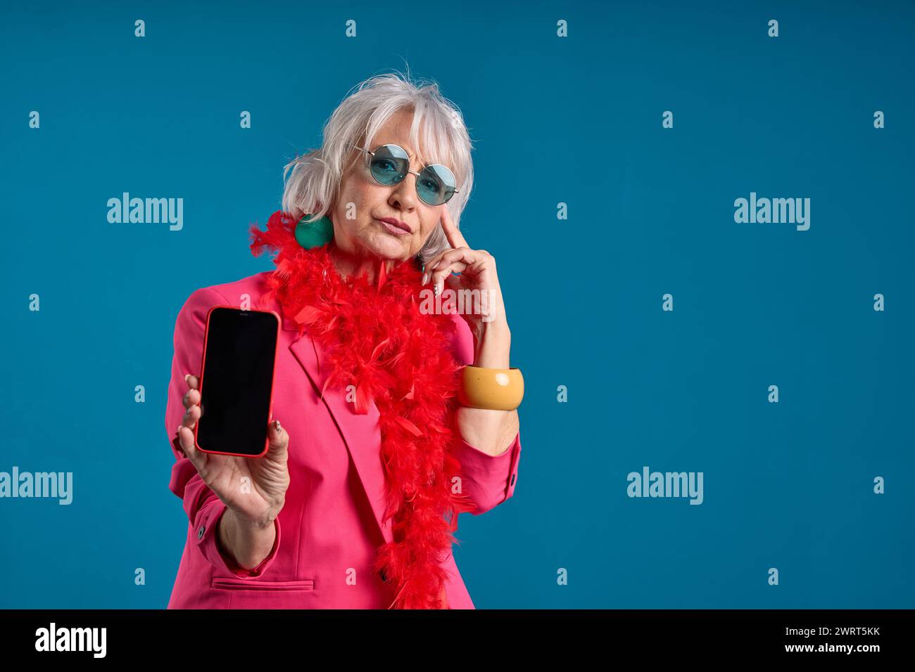 tech-savvy pensative senior lady in trendy pink with smartphone and ...