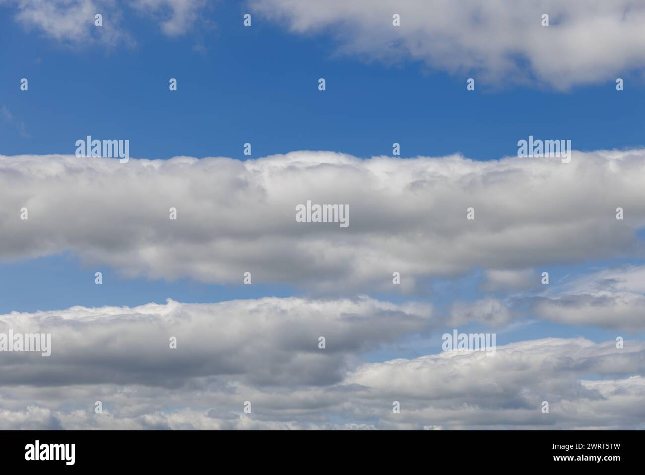 Sky with layers of cumulus clouds, illuminated by a soft, light blue ...