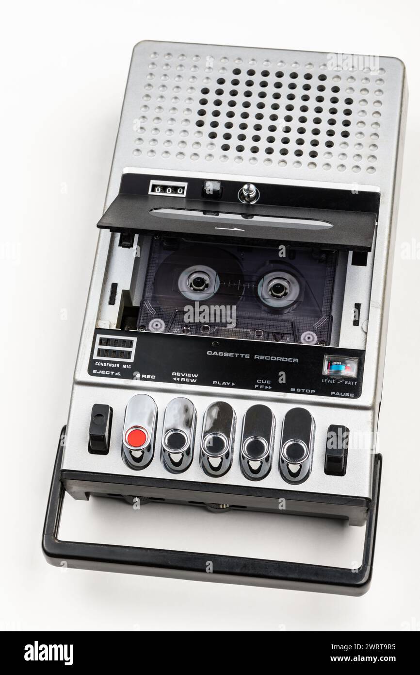 VIntage portable tape recorder with open cover and compact cassette inside compartment. The ...
